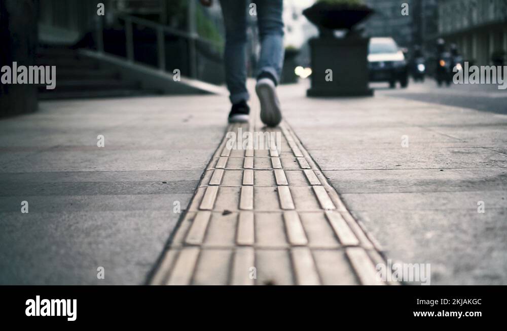 Low angle shot of man walking away, busy street, tactile tiles for ...