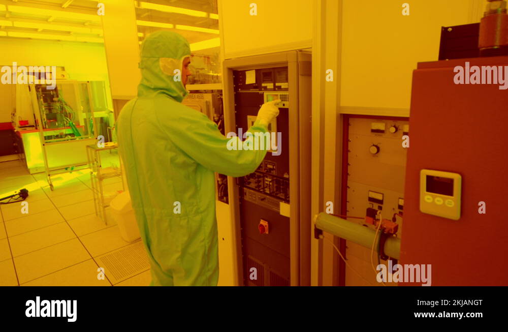 Biotech research worker inside lab wearing PPE adjusts settings on ...