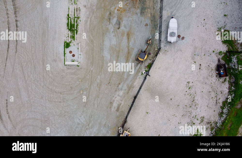 Empty parking lot construction site with yellow digger-loader, drone ...
