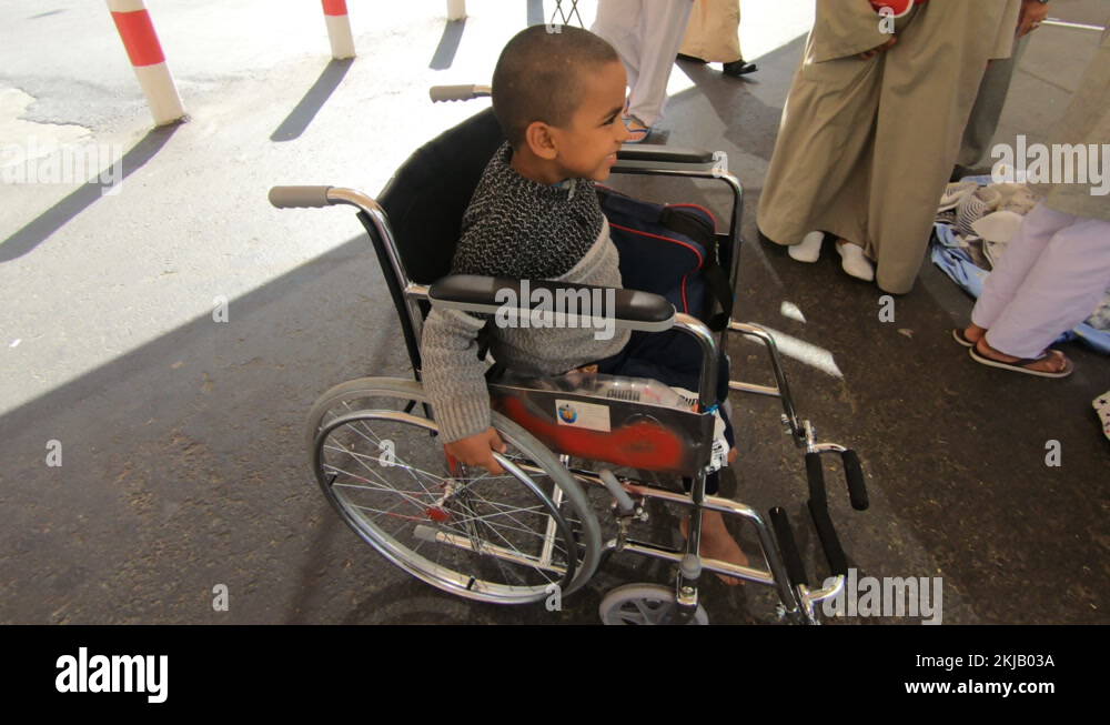 disable boy on a wheelchair moving towards his Muslim parents, Mecca ...