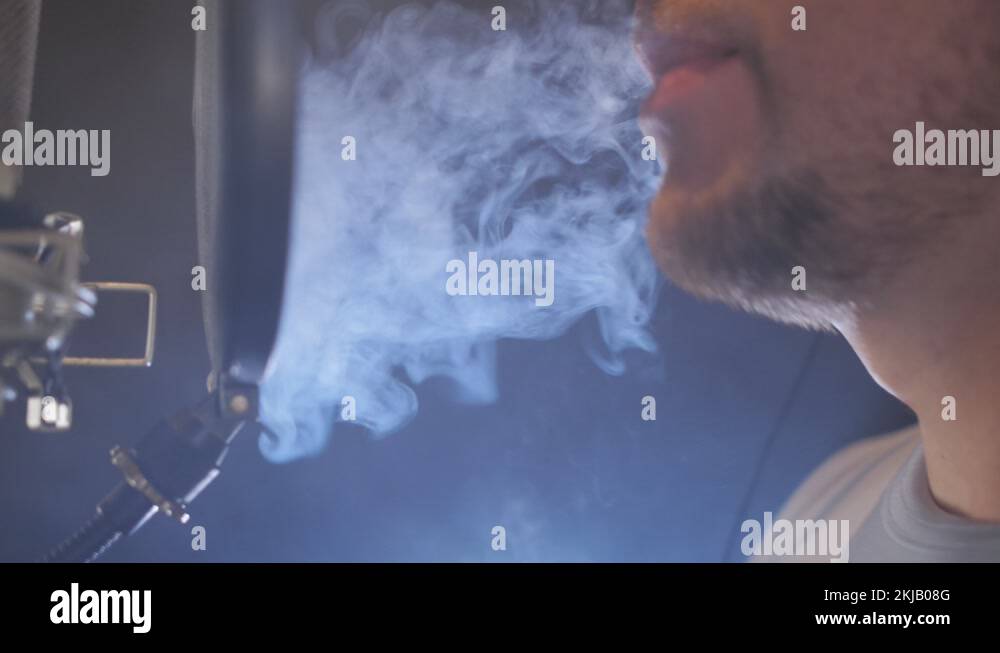 A young man rapper recording this track blowing smoke from his mouth in ...