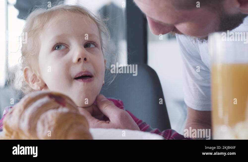 Unrecognizable father wiping face of cute little girl chewing ...