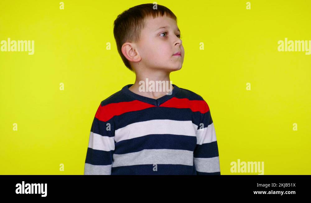 Confused child boy looks around and thinks what to choose by raising ...