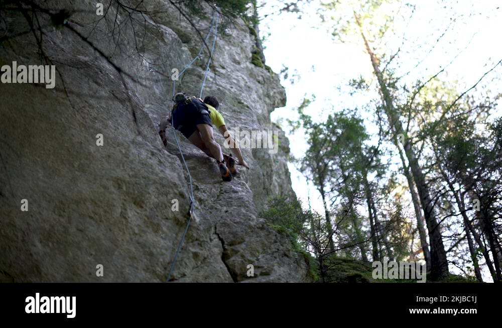 Low angle of cross legged move of rock climber reaching for climbing ...