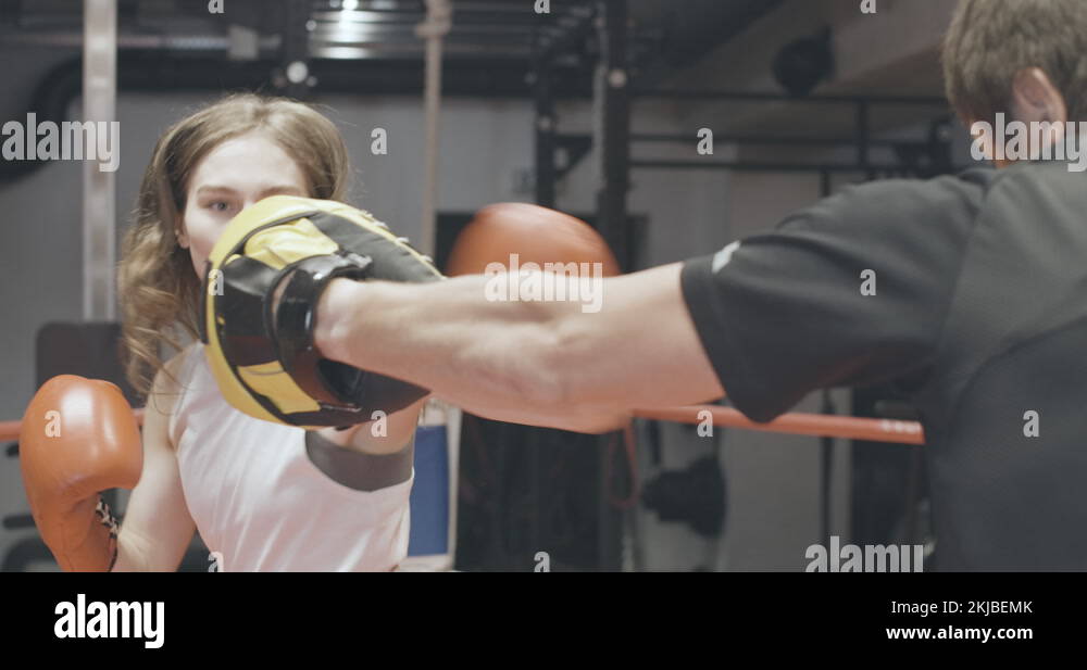 Live camera, confident young female boxer exercising with coach in gym ...