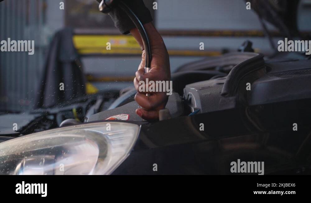 Car mechanic working under the hood in slow motion, putting hose into ...