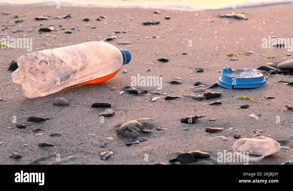 Plastic debris on the sandy beach in surf zone. Plastic pollution of ...