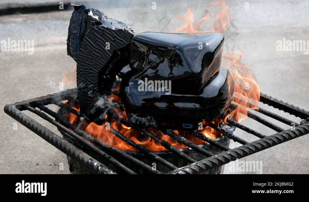 Molten hot tar in bucket on bricks. Roof repair. Fire from bucket. Grid ...