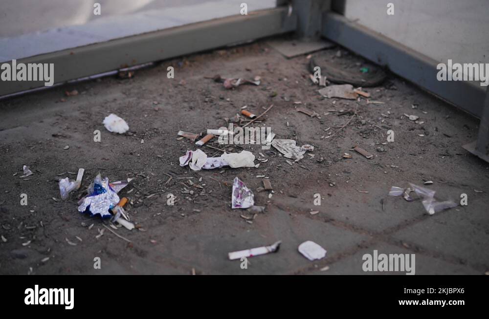 Garbage is lying under the bench at the bus stop. Polluted environment ...