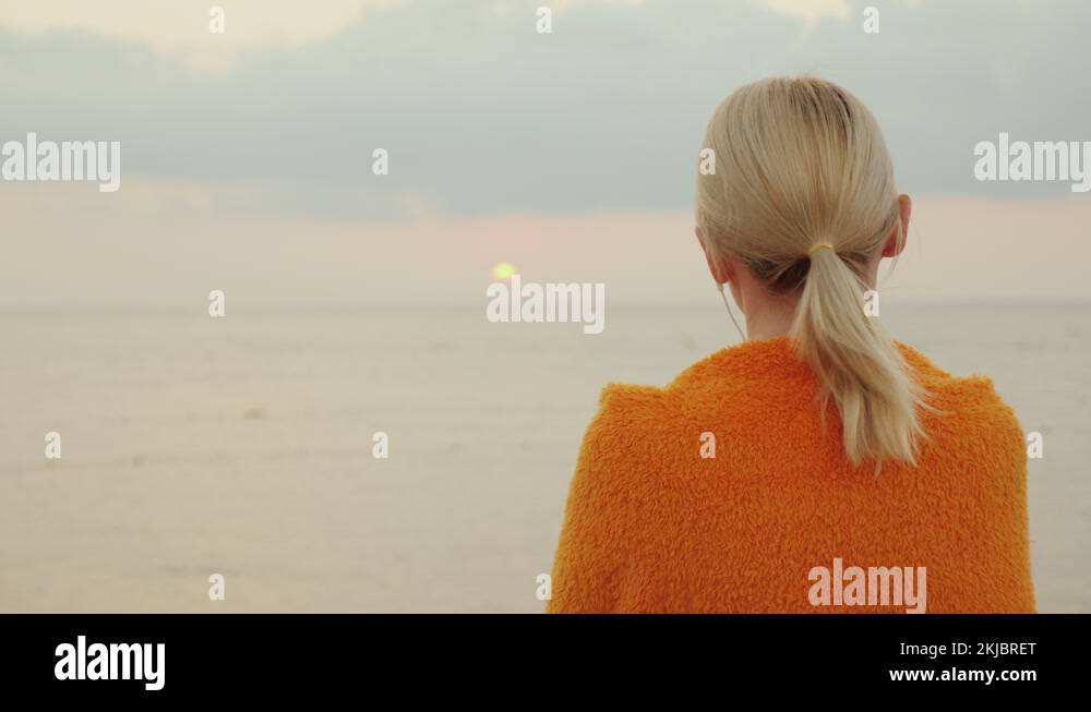 Meet the sunrise at sea alone. A woman wrapped in a blanket looks like ...