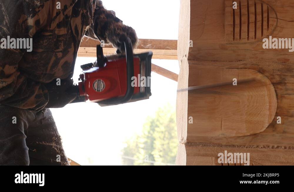 Alignment of window with a chainsaw during the construction of a wooden ...