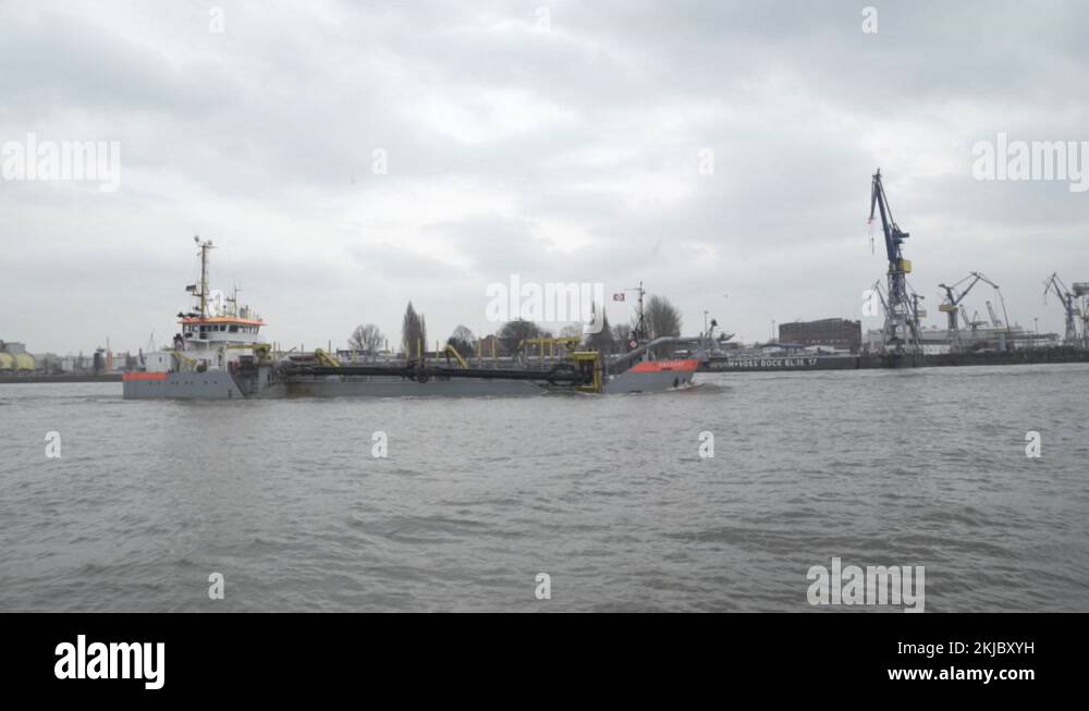long ship with cargo arriving at city port , grey sky with clouds work ...