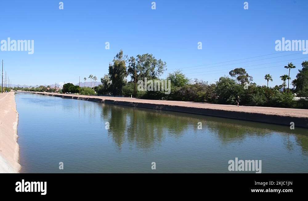 Pan from walker on the far side of the Arizona Canal Trail to the near ...