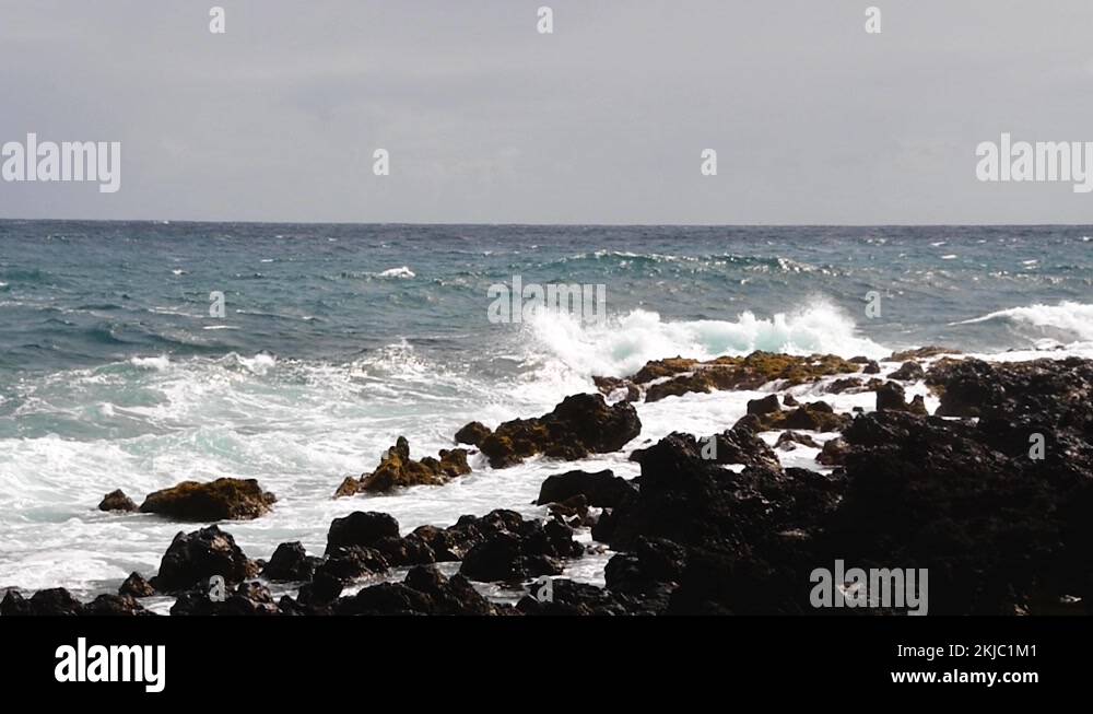 A slight tilt-down on waves splashing over the Hawaiian volcanic rock ...