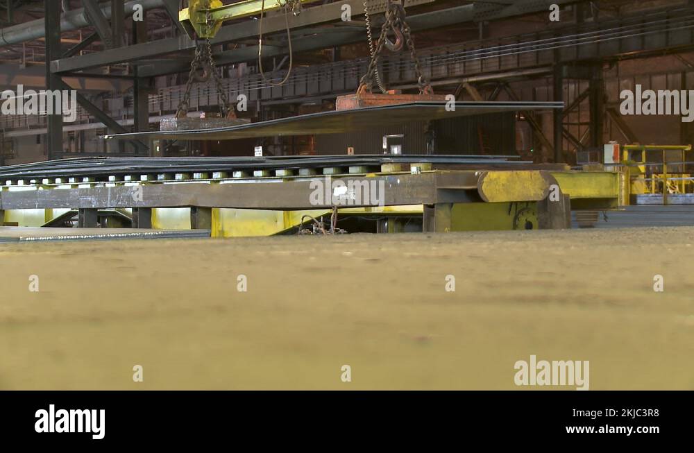 Electromagnet crane at steel mill lifts and move new steel plates into ...