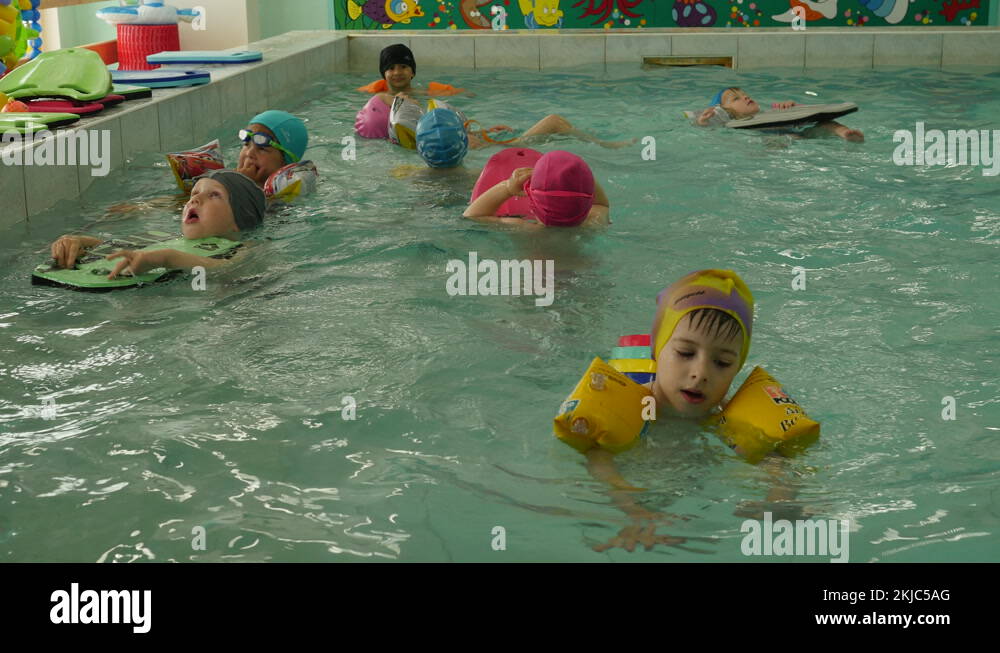 Swimming Practice. Kids learning to swim in swimming pool at ...