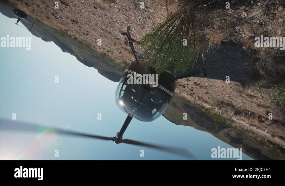 Helicopter starting up propellors turning in the desert with pilot in ...