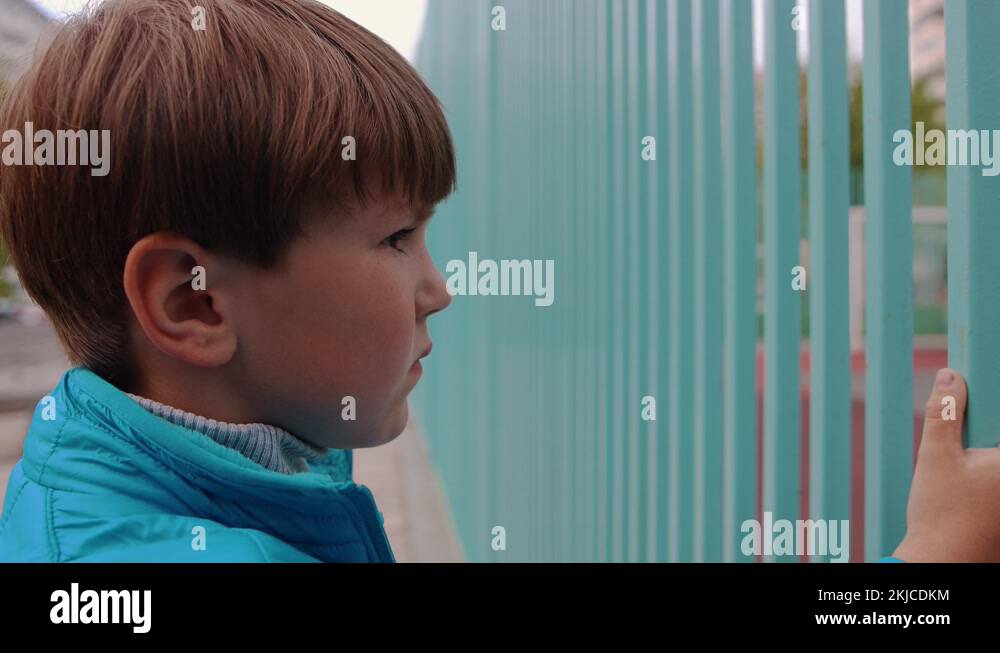 A sad little boy watching another kids playing football behind the ...