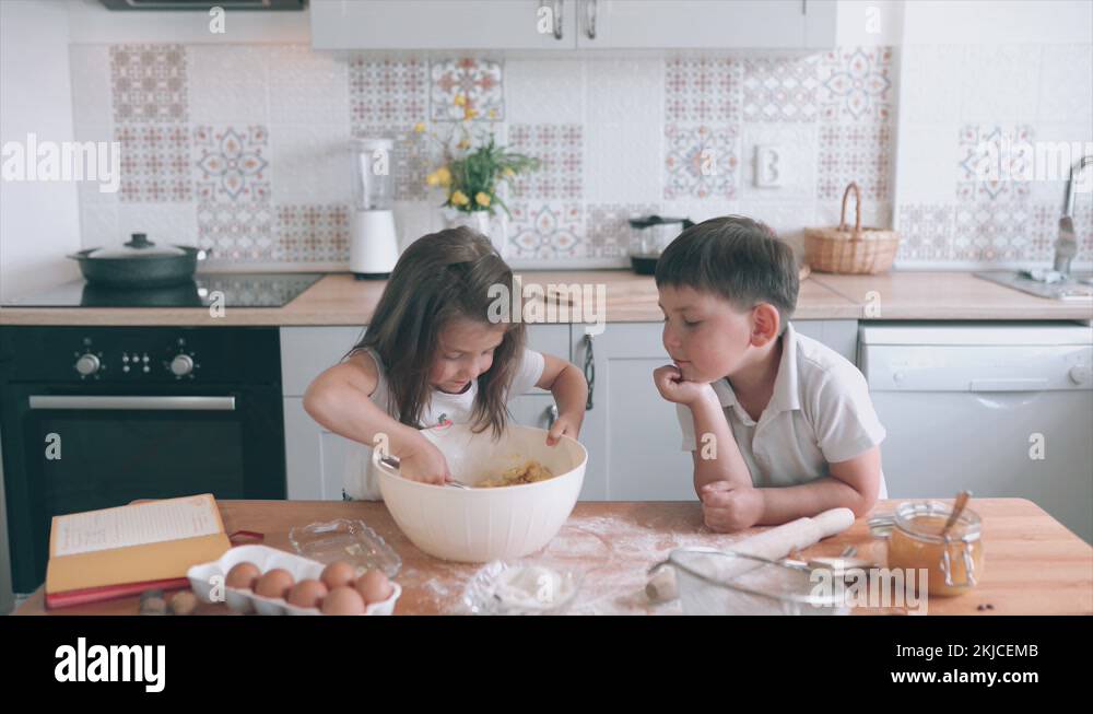 Funny kids cooking together. Girl is beating the dough . Brother and ...