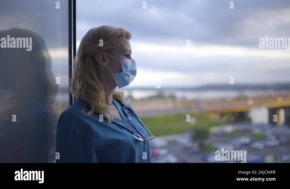 Overworked female doctor taking off face mask, breathing fresh air ...
