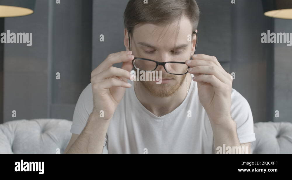 Close-up portrait of tired Caucasian man taking off eyeglasses and ...
