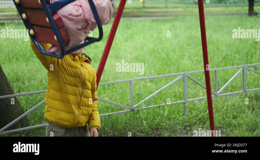 Brother pushing his little sister on swing Stock Video Footage - Alamy