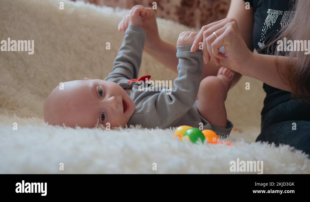 A mother does developmental physical exercises for her newborn baby ...