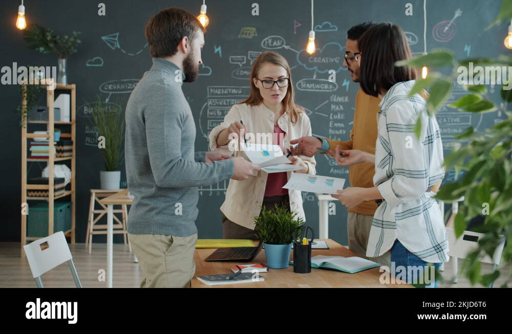 Colleagues men and women sharing business ideas looking at papers in ...