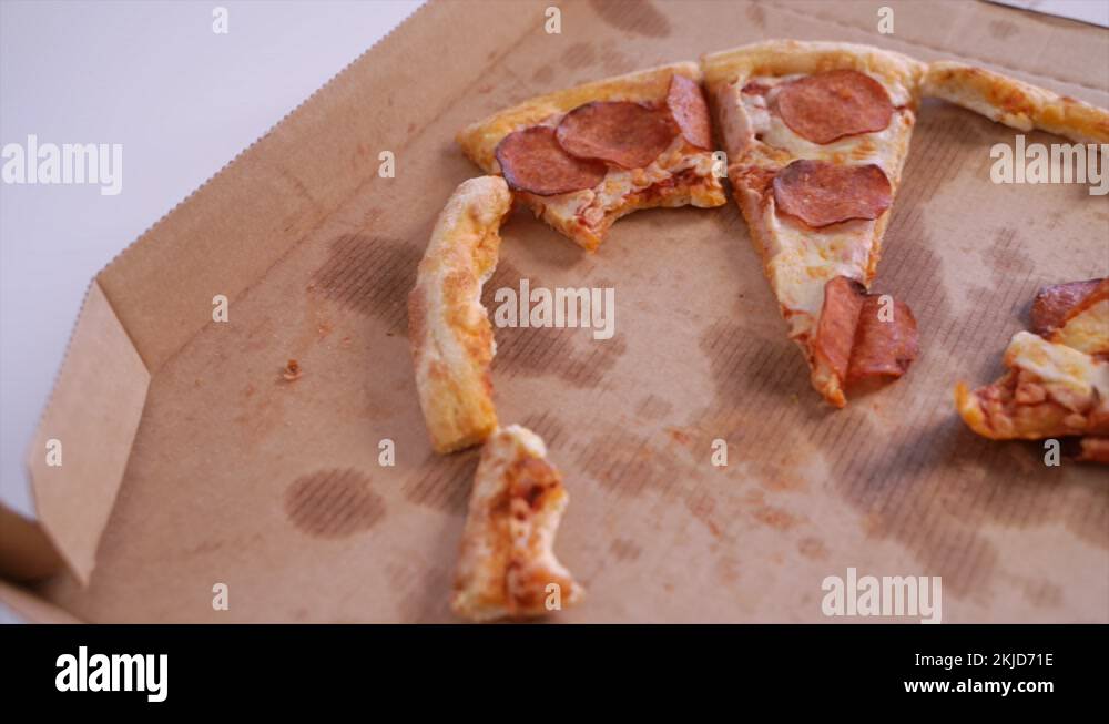 camera slides over a box of Pepperoni pizza with half eaten pieces ...
