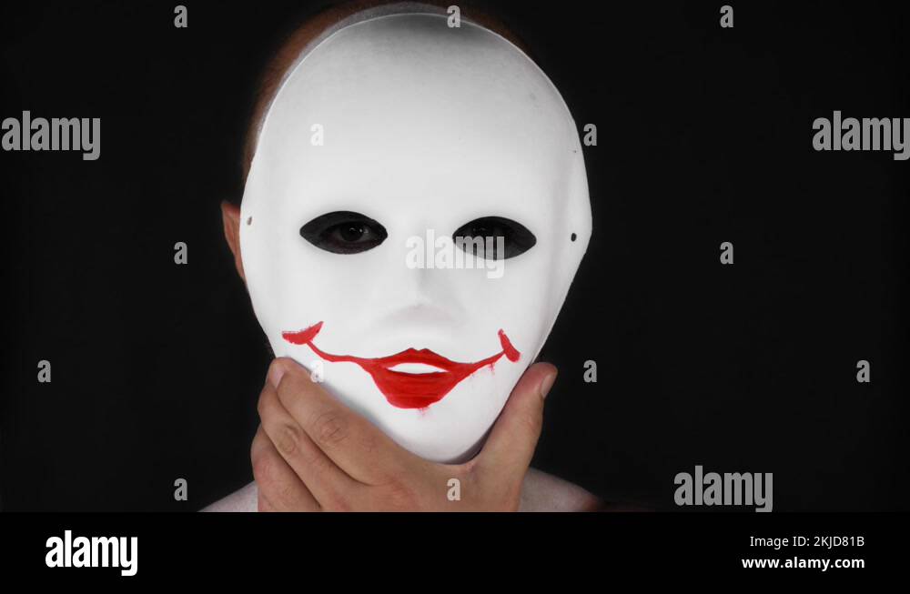 A mime man takes off a white theater mask. Man on a black background ...