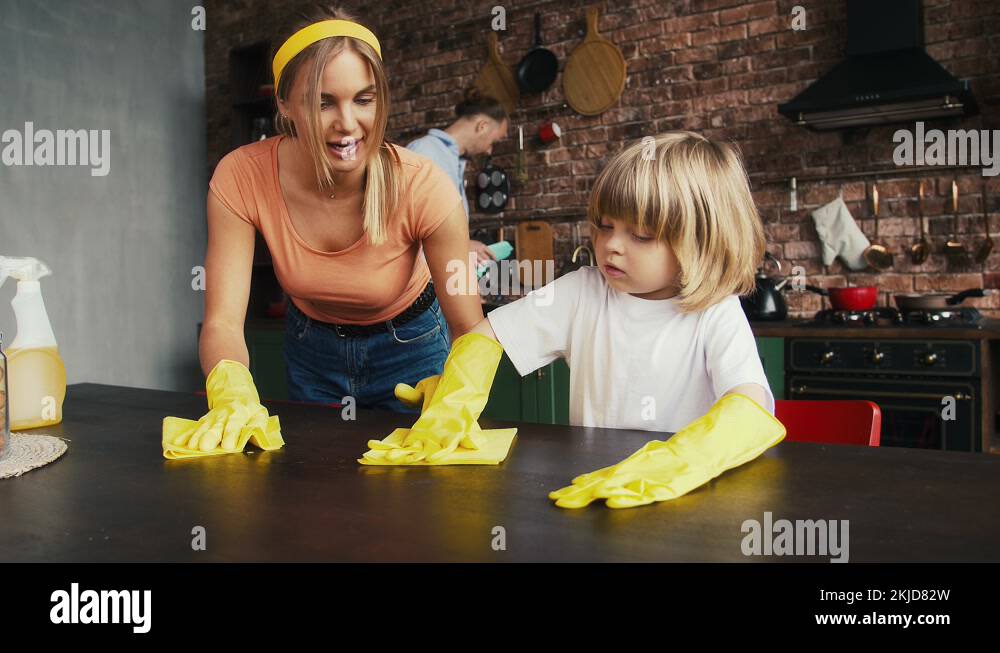 Mother and son in yellow rubber gloves are smiling and talking ...