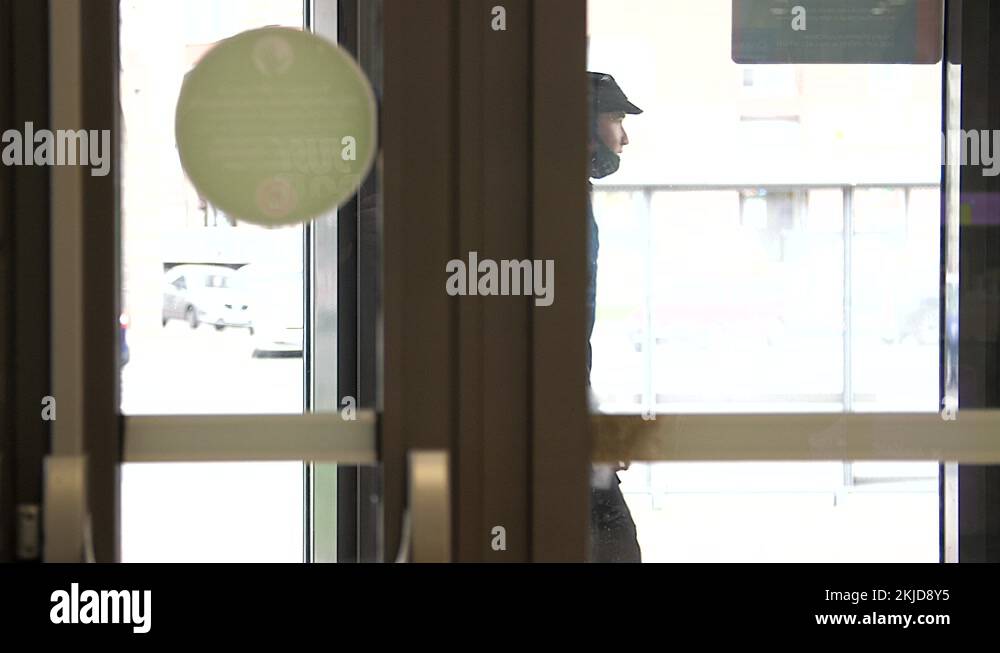 Courier food delivery man enters the building through glass doors Stock ...