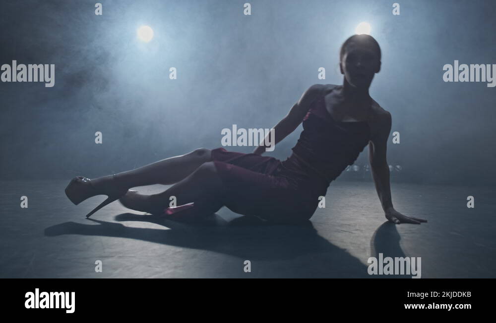 Dancer at smoky stage with spotlights. Woman performing modern dance in ...