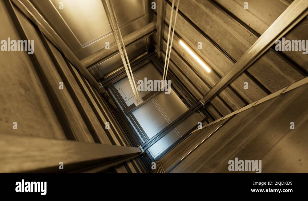 Elevator cabin in a shaft with bare concrete walls and moving cables ...