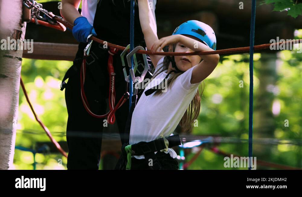 Extreme rope adventure in the park - a little girl in full protection ...