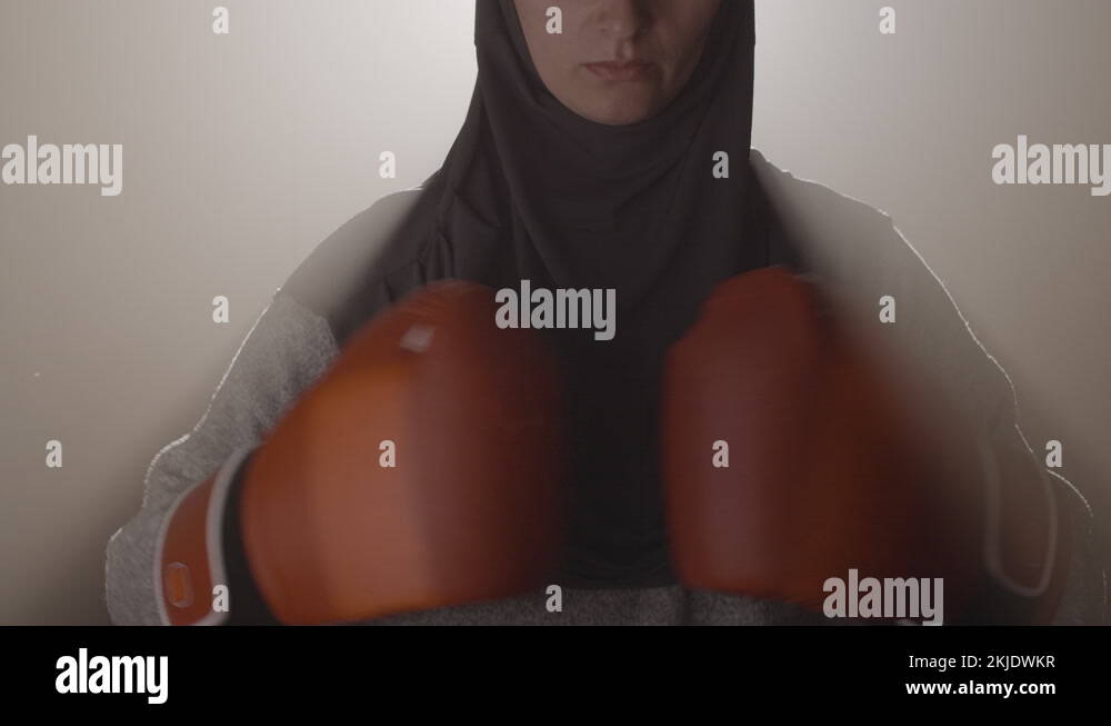 Close-up portrait of confident muslim female boxer punching boxing ...
