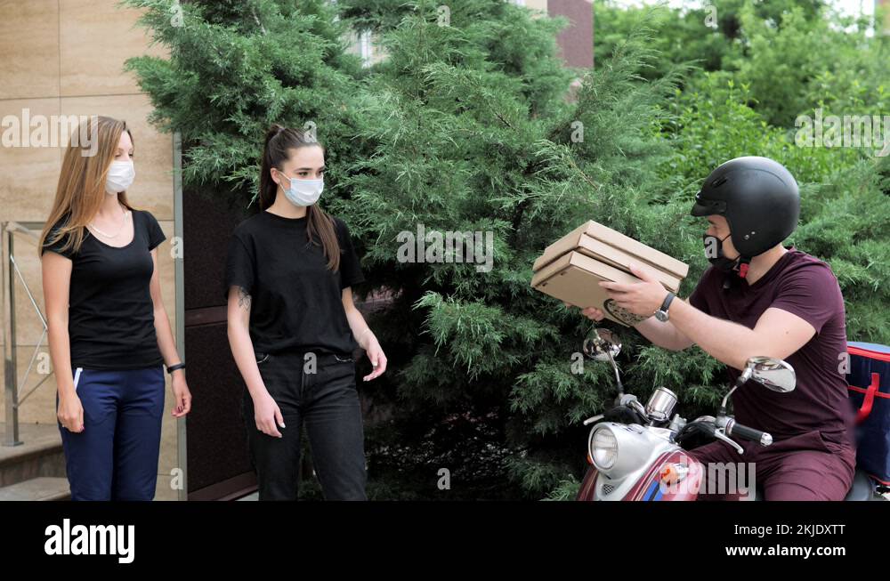 Two girls pick up delivery food box from delivery rider with scooter in ...