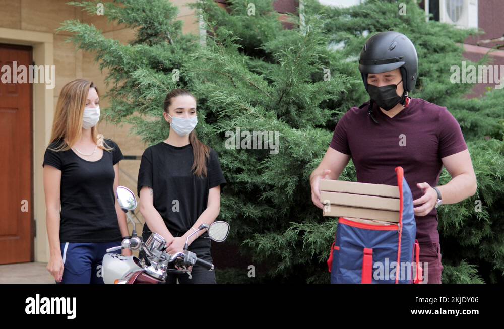 Two girls pick up delivery food box from delivery rider with scooter in ...