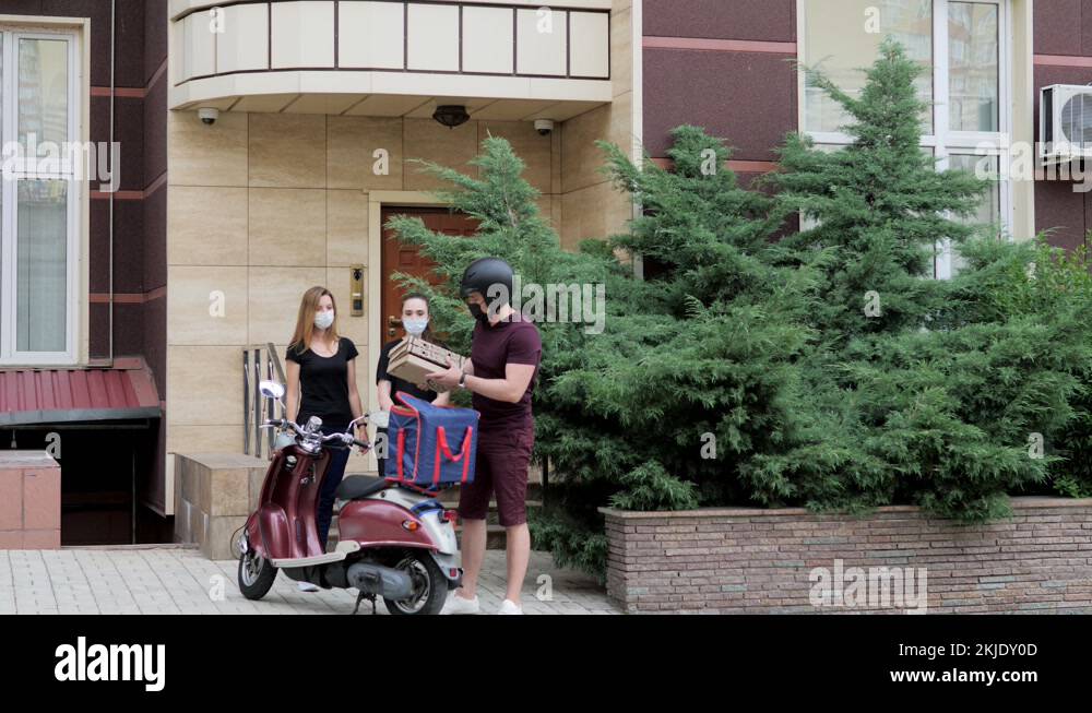 Two girls pick up delivery food box from delivery rider with scooter in ...