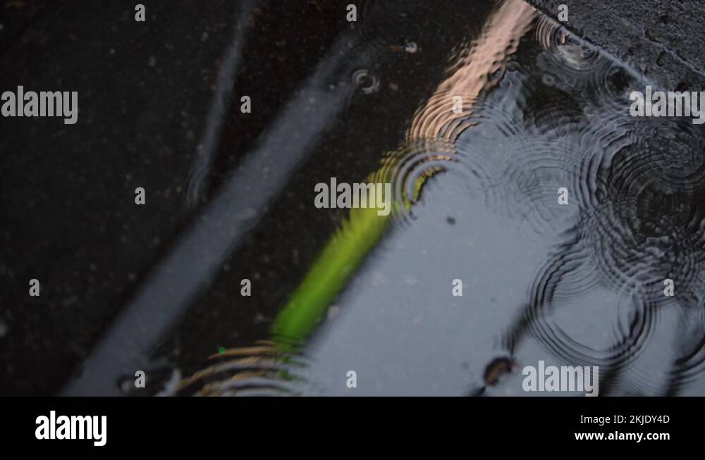 Rain water drops splashing on road pavement with flicking light ...