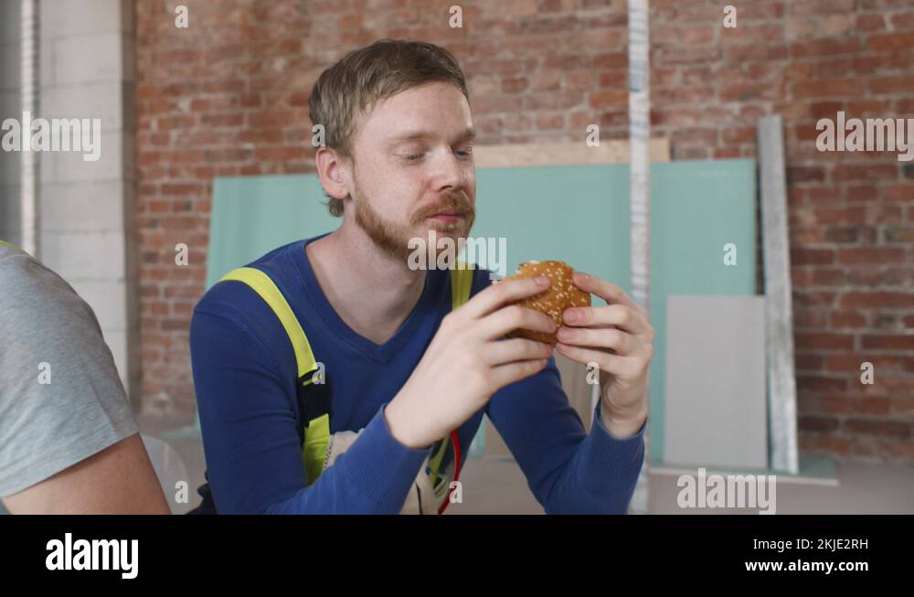 Worker wearing uniform eating burger during lunch break Stock Video ...