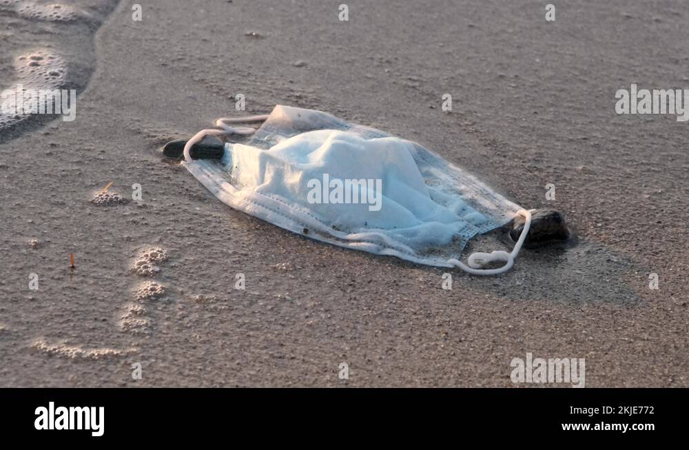 Disposable face masks and plastic debris on the beach in surf zone ...