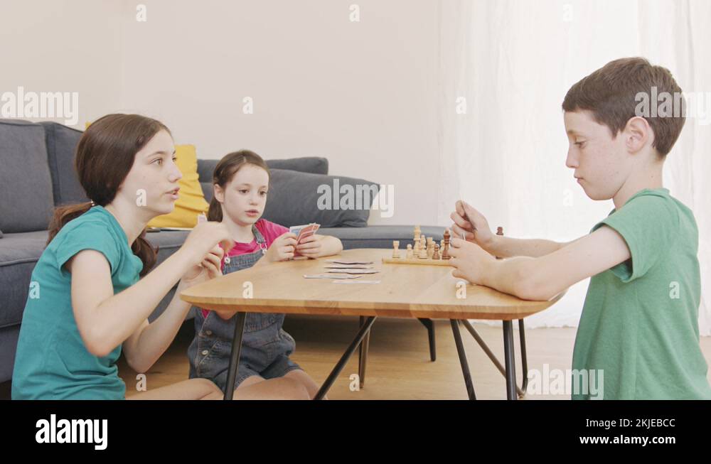 Three kids playing a card game in the living room, shouting and arguing ...