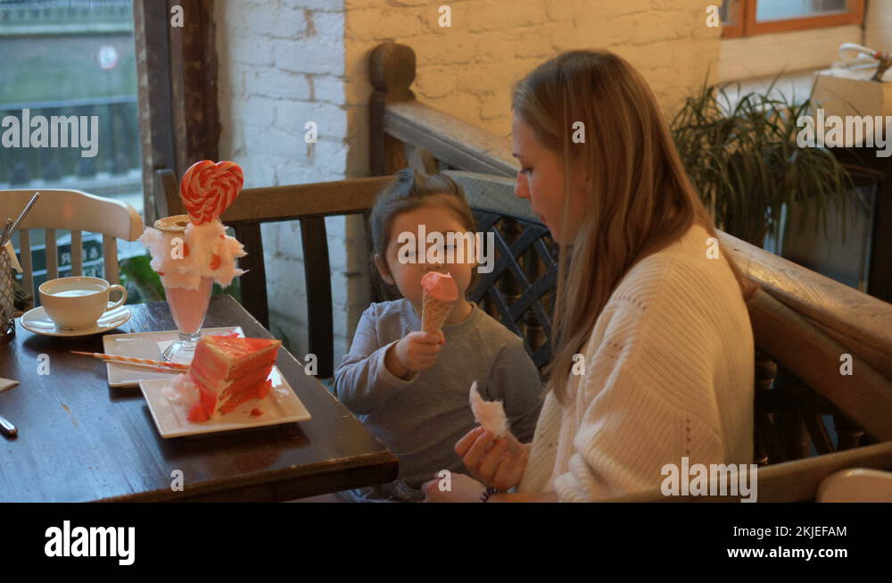 mother and daughter eat sweets in a cafe. Little girl treats a girl ...