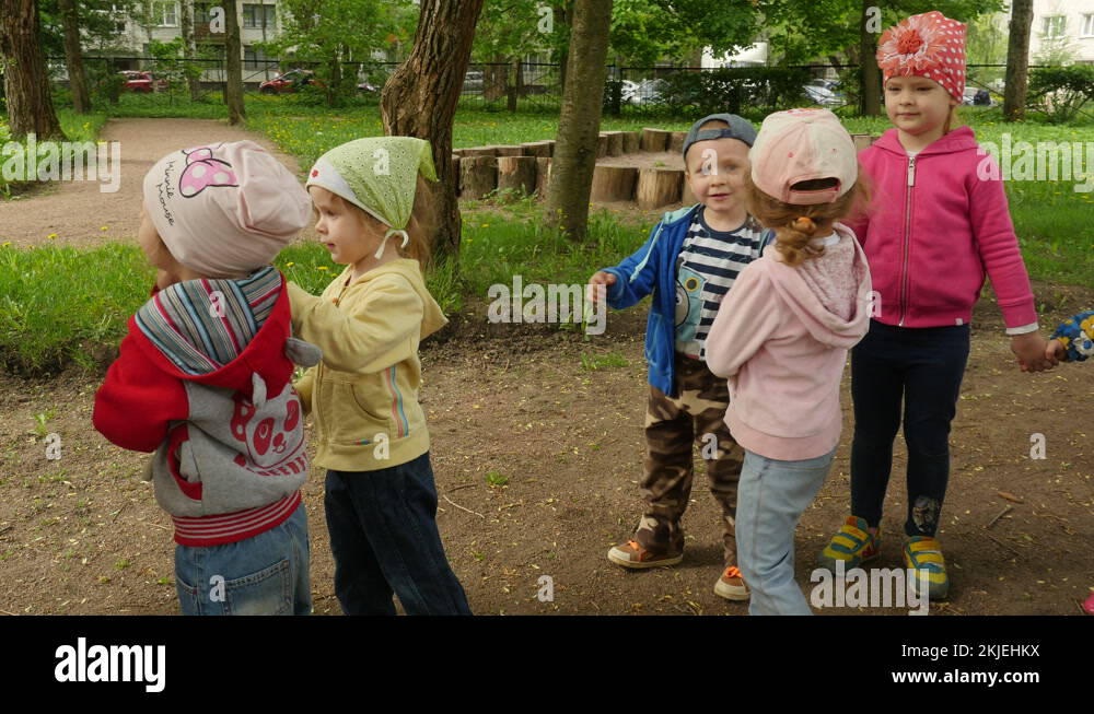 Children walk on kindergarten yard holding hands. Group of kids on the ...
