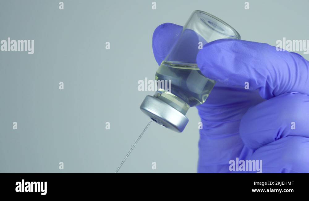Doctor drawing up solution from vaccine bottle and filling syringe ...