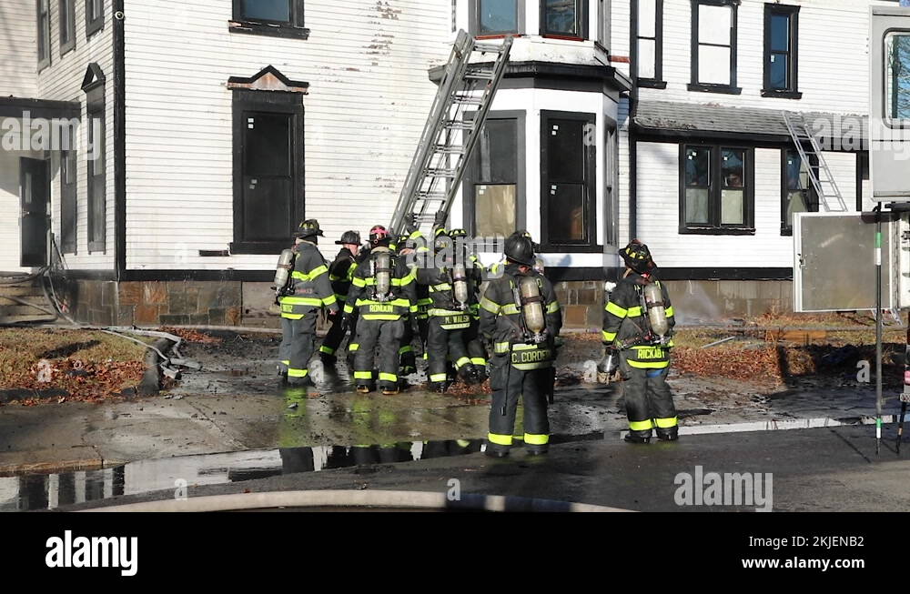 A Large Team of Firefighters Working Together to Stand Up a Ladder Next ...