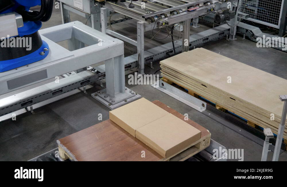 Furniture factory. An automated machine packaging furniture parts in ...