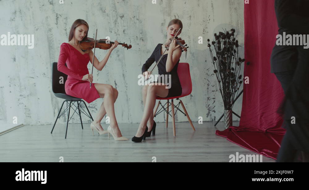 Two elegant girls playing the violin, couple of dancers performs tango ...