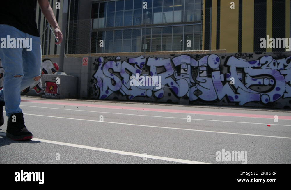 Young man walking on athletics track. Background with graffiti walls ...